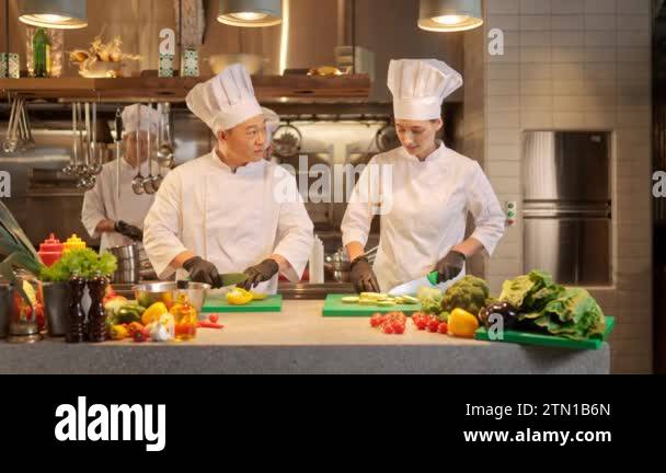 Male and female cooks cooking together at workplace on background of ...