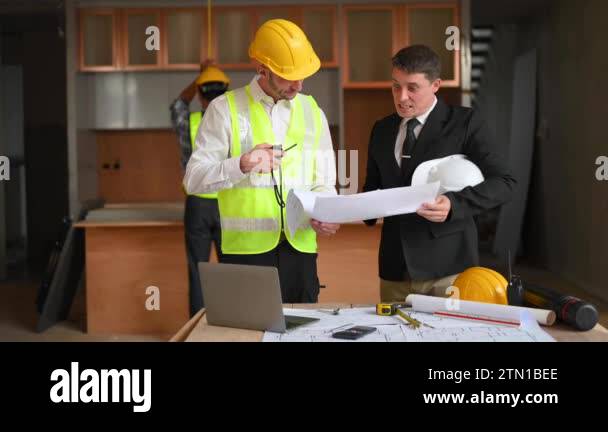 Contractor and architect looking at plan and talking about working on ...