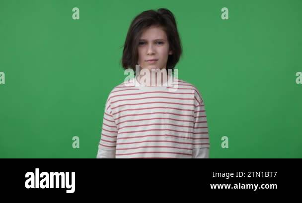Young boy standing on a green screen background, shaking his head and ...