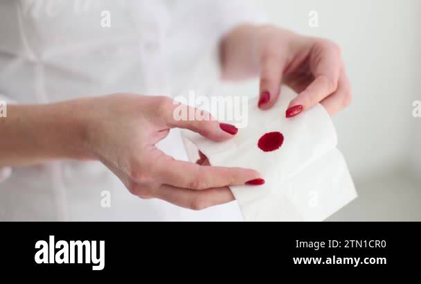 Woman holds paper tissues with blood stain in light premise. Female ...
