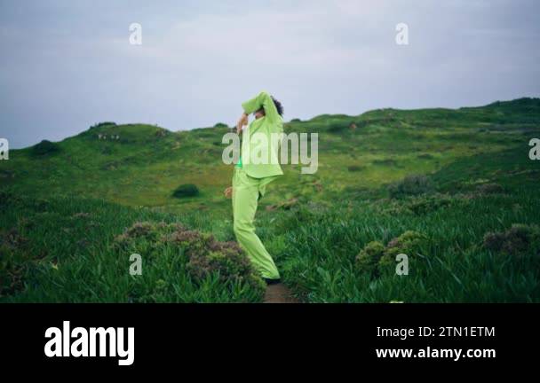 Stylish girl performer dancing at cloudy nature in trendy green suit ...