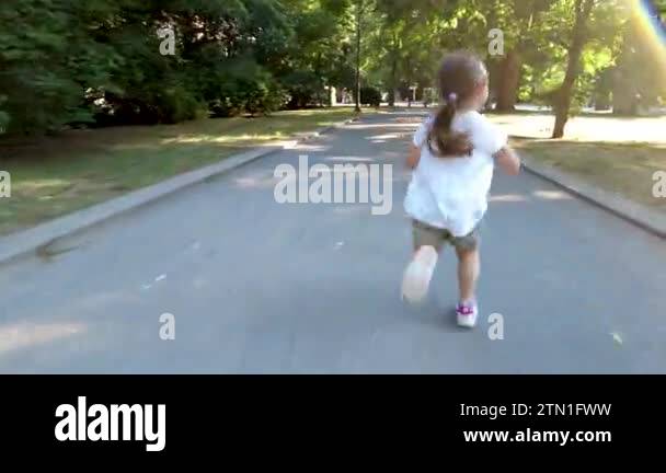 Little girl running outside in the park. Playing chase with his father ...