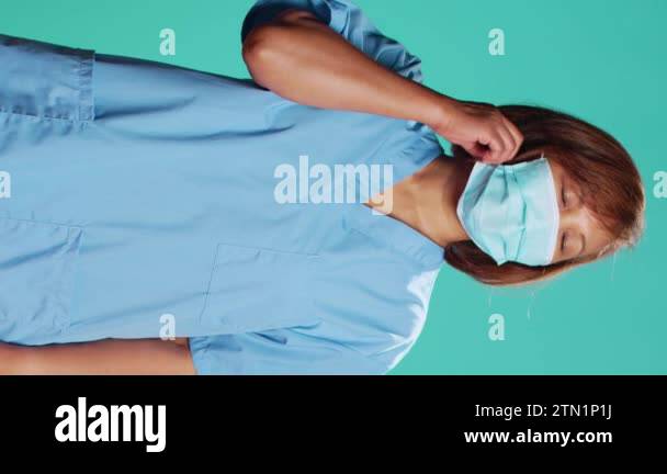 Tired nurse taking off protective face mask after finishing hospital ...