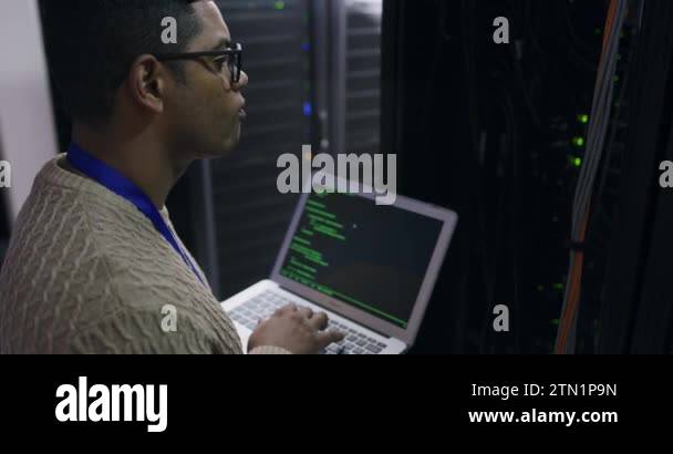 Man in server room with laptop, coding and network administration, engineer in digital storage ...