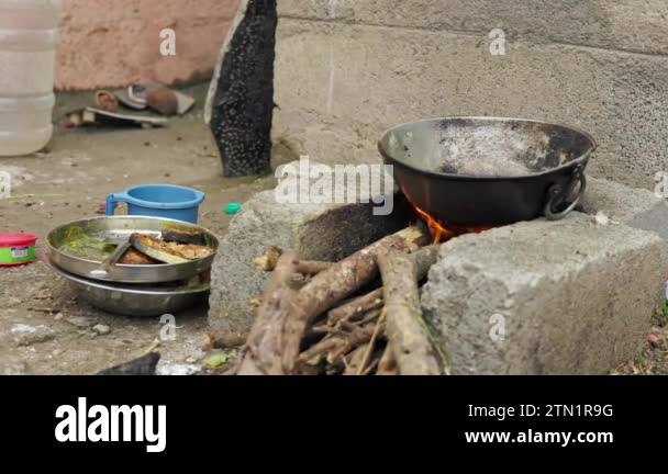 Closeup of frying the fish pieces in the pan on the brick stove in ...