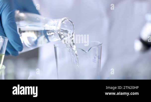 Scientist chemist pouring water from flask into glass 4k movie. Water ...