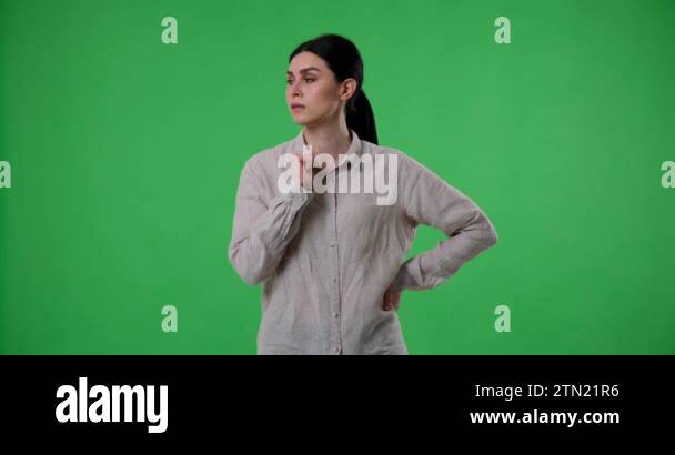 A confused woman of Caucasian ethnicity stands on a green screen ...