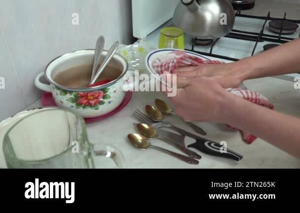 Woman hands with dry towel wipe dishes in surface table close-up ...