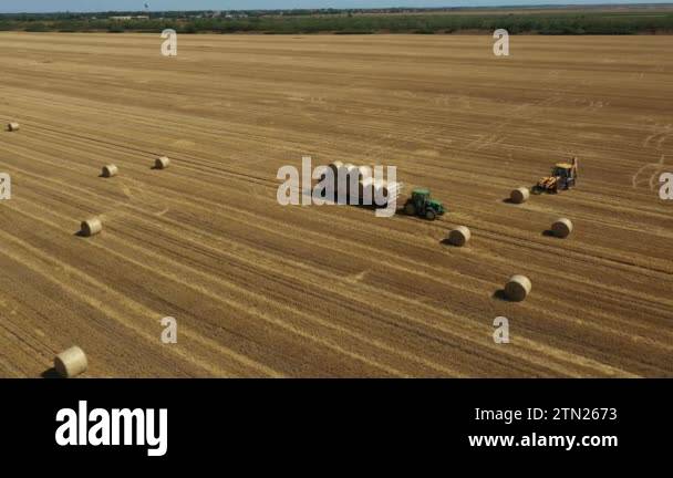 Above view, dolly move orbit around excavator as loading straw bales on ...
