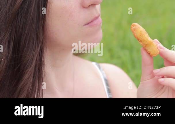 The girl eats chicken strips or nuggets. Hungry young woman eating fast ...