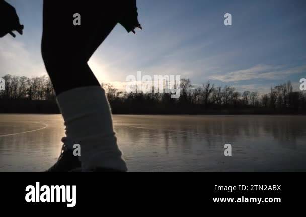 Two young people in figure skates sliding on ice during sunset. Man and ...