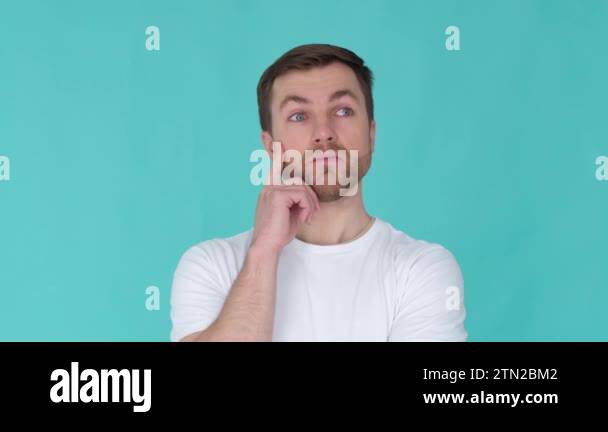 Confused young guy in white t-shirt scratching his head thinking how to ...