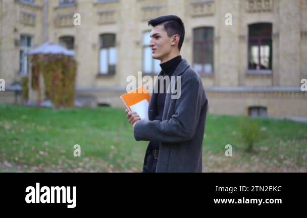 Side view positive Caucasian man walking at university campus greeting ...