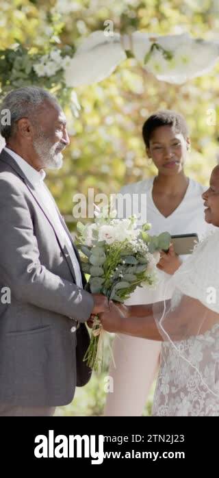 Vertical video of african american woman officiating wedding for senior biracial couple, slow ...