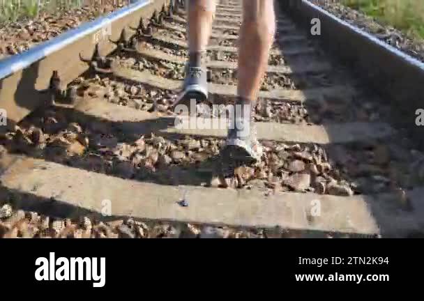 Male feet are running between rails on railroad tracks. Sprinting ...
