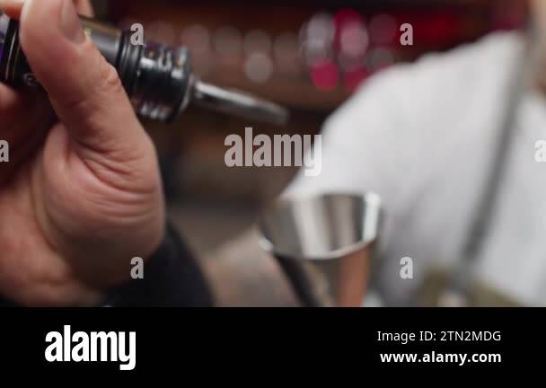 Slow motion video of bartender pouring alcohol from a bottle into a jigger at a bar. Preparation ...