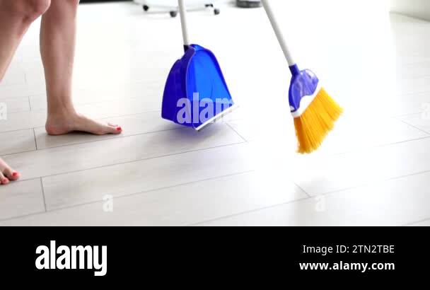 Woman sweeping floor with broom and dustpan closeup 4k movie slow motion. Apartment cleaning and ...