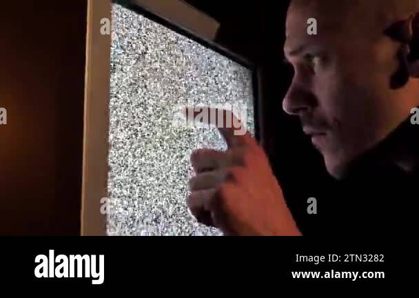 A man with a puzzled expression is trying to fix a broken old TV. Close ...