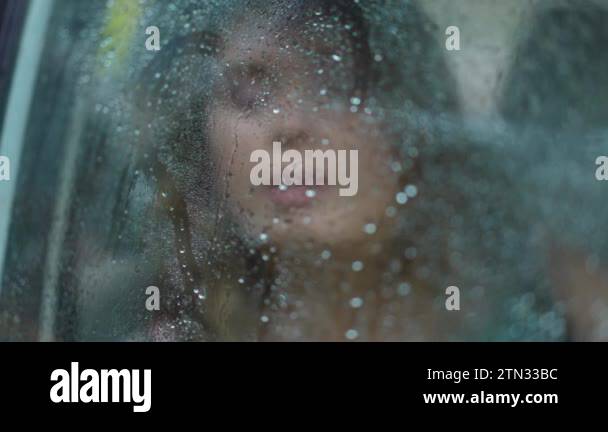 Close-up car window with raindrops and female Caucasian hand touching ...