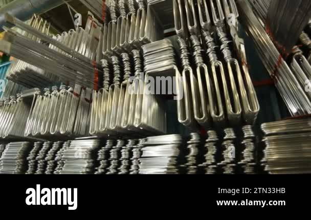 Camera moves along row with finished metal fridge pipes on shelves in ...