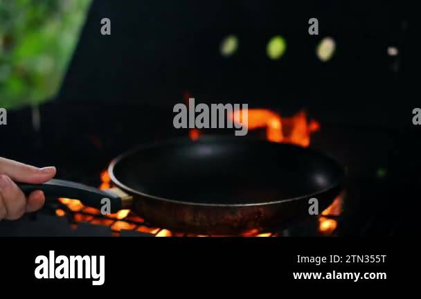 Close-up burning fire in grill with male hand placing frying pan ...