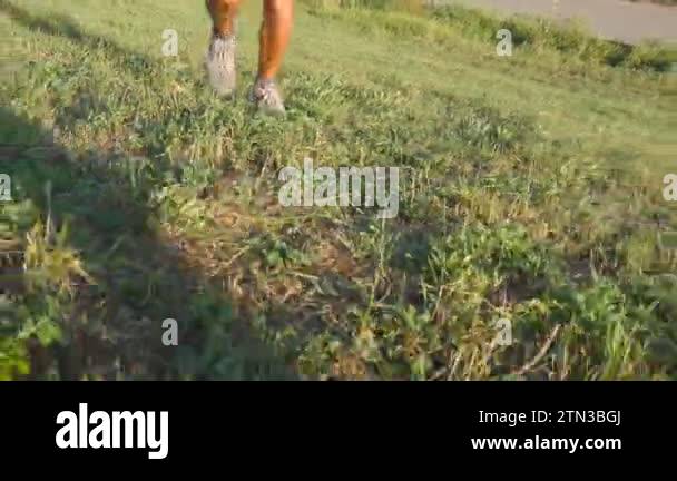 Male feet running over green hill. Legs of athlete is jogging in nature ...