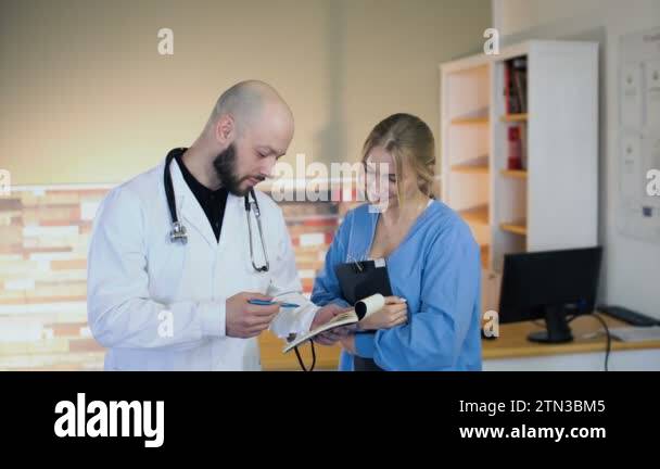 30s bald doctor duscuss with 20s blonde nurse in medical uniform at ...