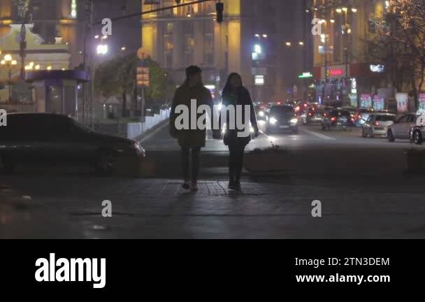 Happy teenagers in love walking in night city street, holding hands and ...