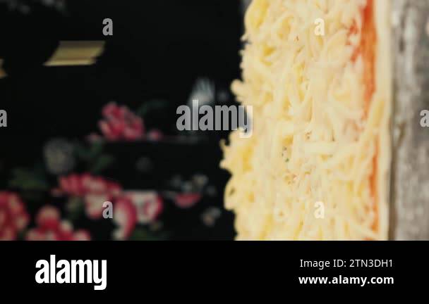Adding grated cheese on pizza dough, close up of hands and cheese ...