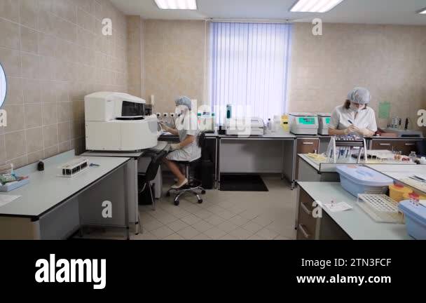 Two medical assistans in white coats, protective masks and caps working ...