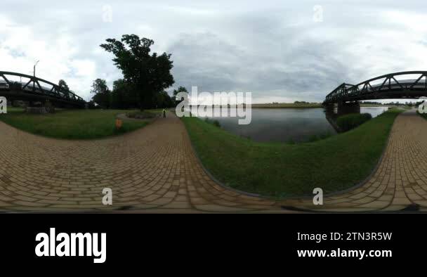 360Vr Video Man Walking by Paving Stones River Bank Green Grass Cars on Bridge Through River ...