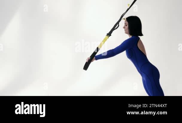 A fit woman performs push-ups on loop resistance bands, challenging her ...