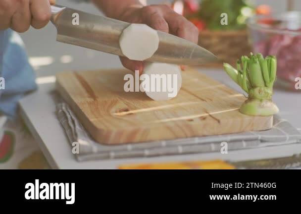 Cooking - Chef's hand cutting white radish on a chopping board in the ...