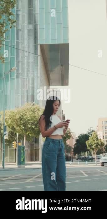 Young woman uses map app on mobile phone while standing on modern city ...
