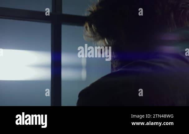 Male criminal leans head and stands facing the metal bars in prison ...