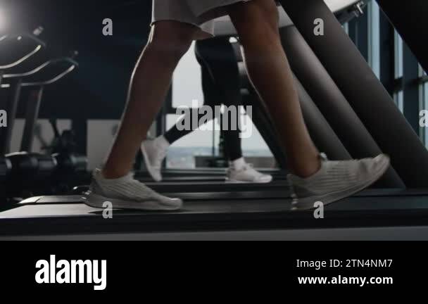 Side view legs in sneakers walk on treadmill in fitness gym unknown ...