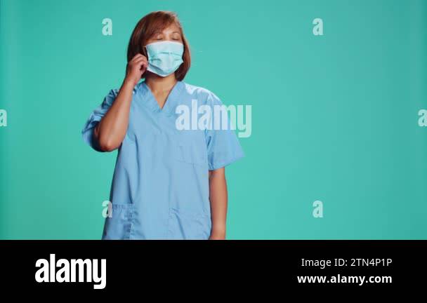 Tired nurse taking off protective face mask after finishing hospital ...