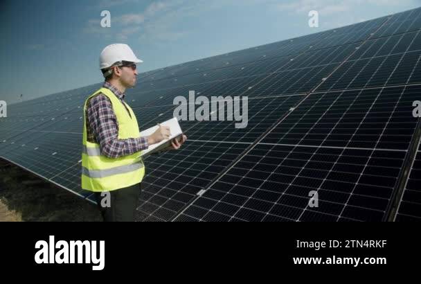 Technician inspect Solar cell Farm through field of solar panels, checking the panels at solar ...