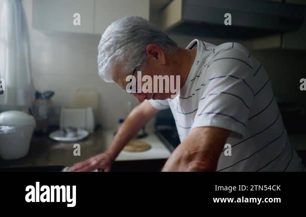 Mature man standing at kitchen counter struggling with old age and ...
