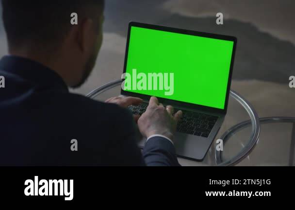 Businessman typing on keyboard while working on laptop with green ...