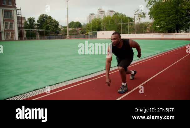 An athletic man with Black skin in a black sports uniform starts his ...