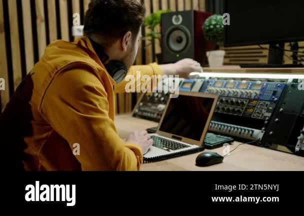 young sound engineer works in music studio with monitors and equalizer ...