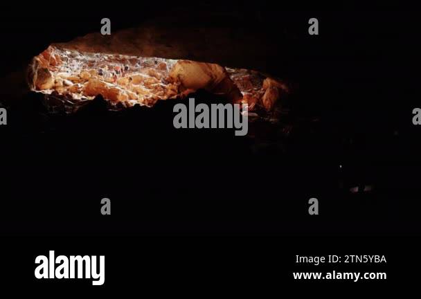 A group of tourists is seen leaving the dark cave in a well-organized ...