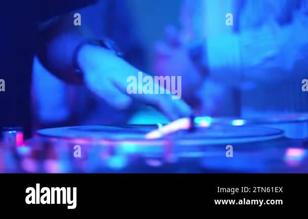 DJ mixes tracks on DJ console lit color music in nightclub party. Dj ...