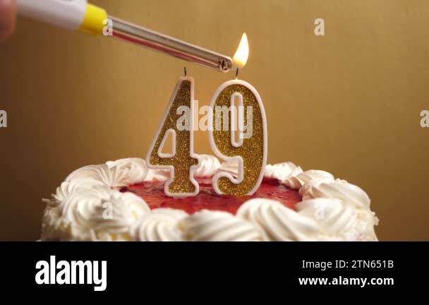 A candle in the form of the number 49 is lit, which is stuck into the ...
