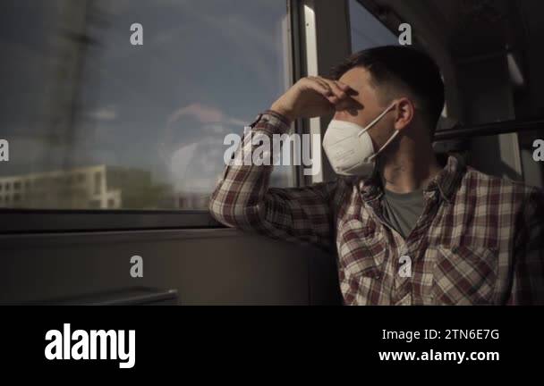Sad, tired man in mask sitting by window on suburban train in Germany ...