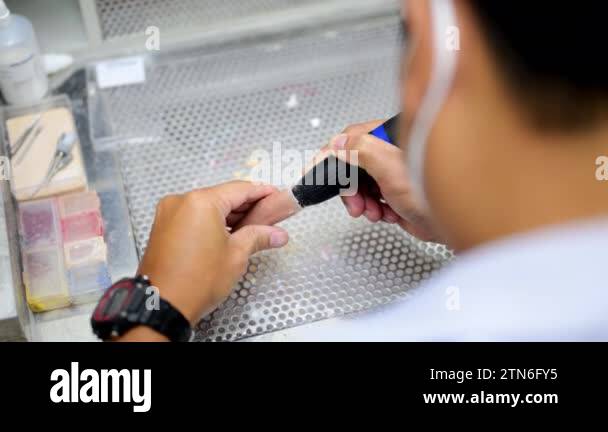 Technician making prosthetic device using grinder to smooth socket ...