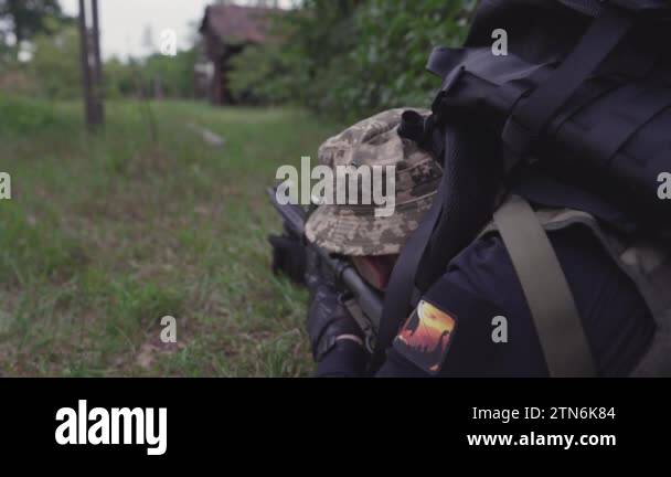 A man in military gear looking through the scope of his assault rifle ...