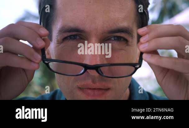 Close up man with poor eyesight puts on eyeglasses to see better ...