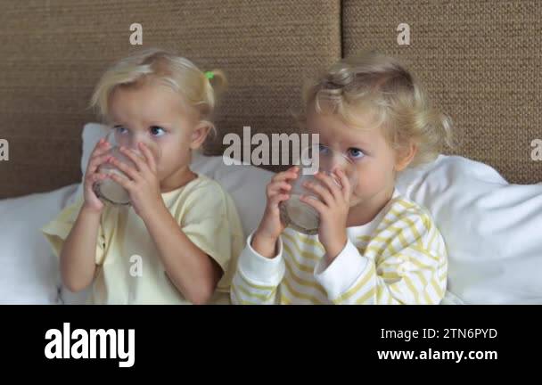 Two Caucasian blonde twin girls drink refreshing cold healthy drink to ...
